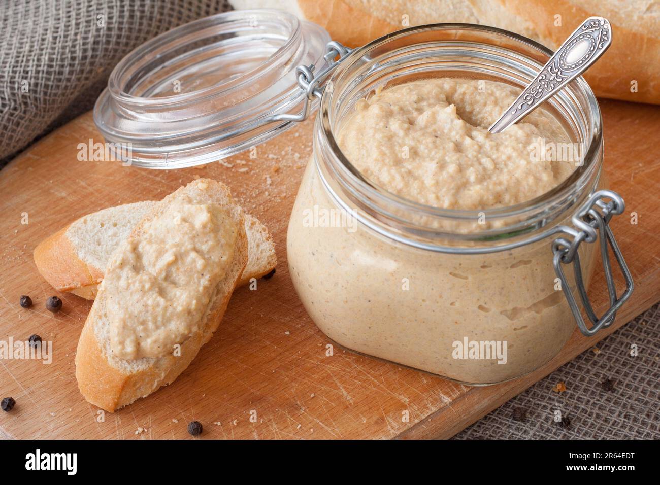 Fresh homemade mushroom pate in a jar and on a baguette slice on a ...