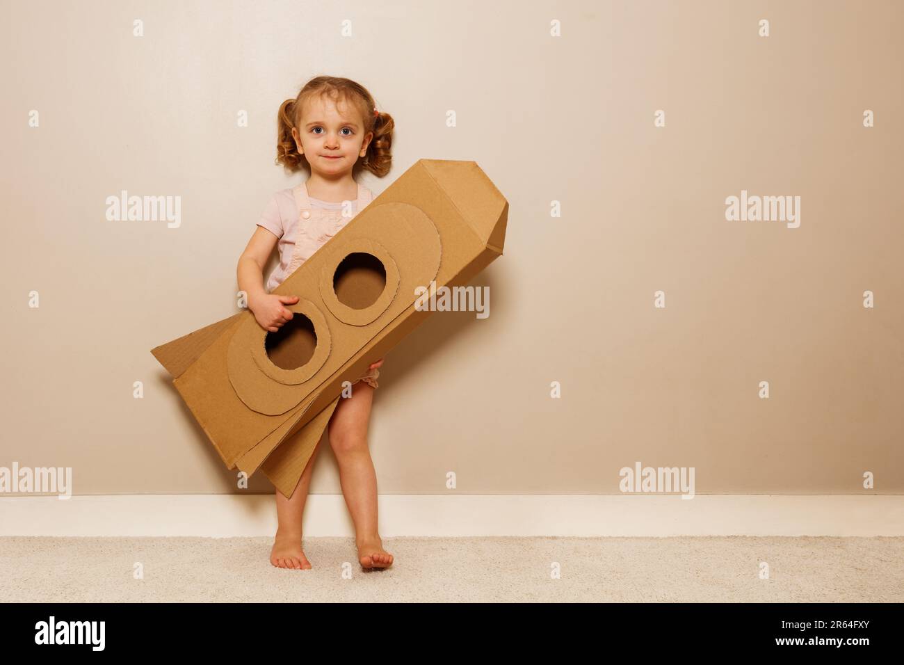 Young girl holds cardboard rocket, imagines space voyage Stock Photo ...