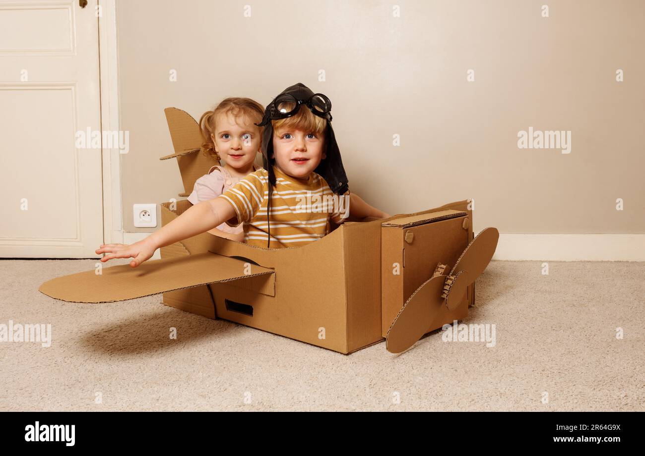 Children sit in cardboard plane wear hat and glasses pretend fly Stock ...