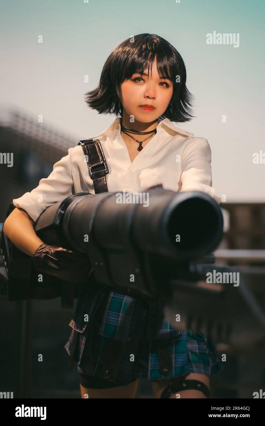 A young Asian woman stands outdoors in a white shirt and patterned ...