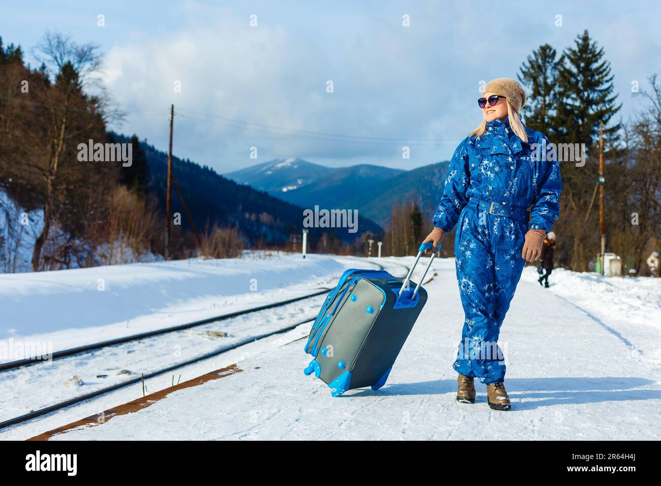 Woman pulling heavy luggage at a snow train station. Travelling by ...