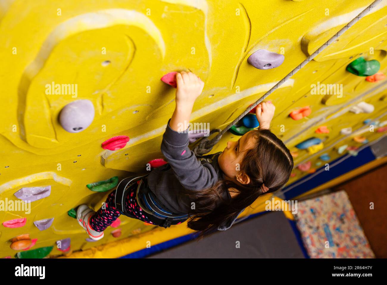 little girl climbing a rock wall indoor Stock Photo - Alamy