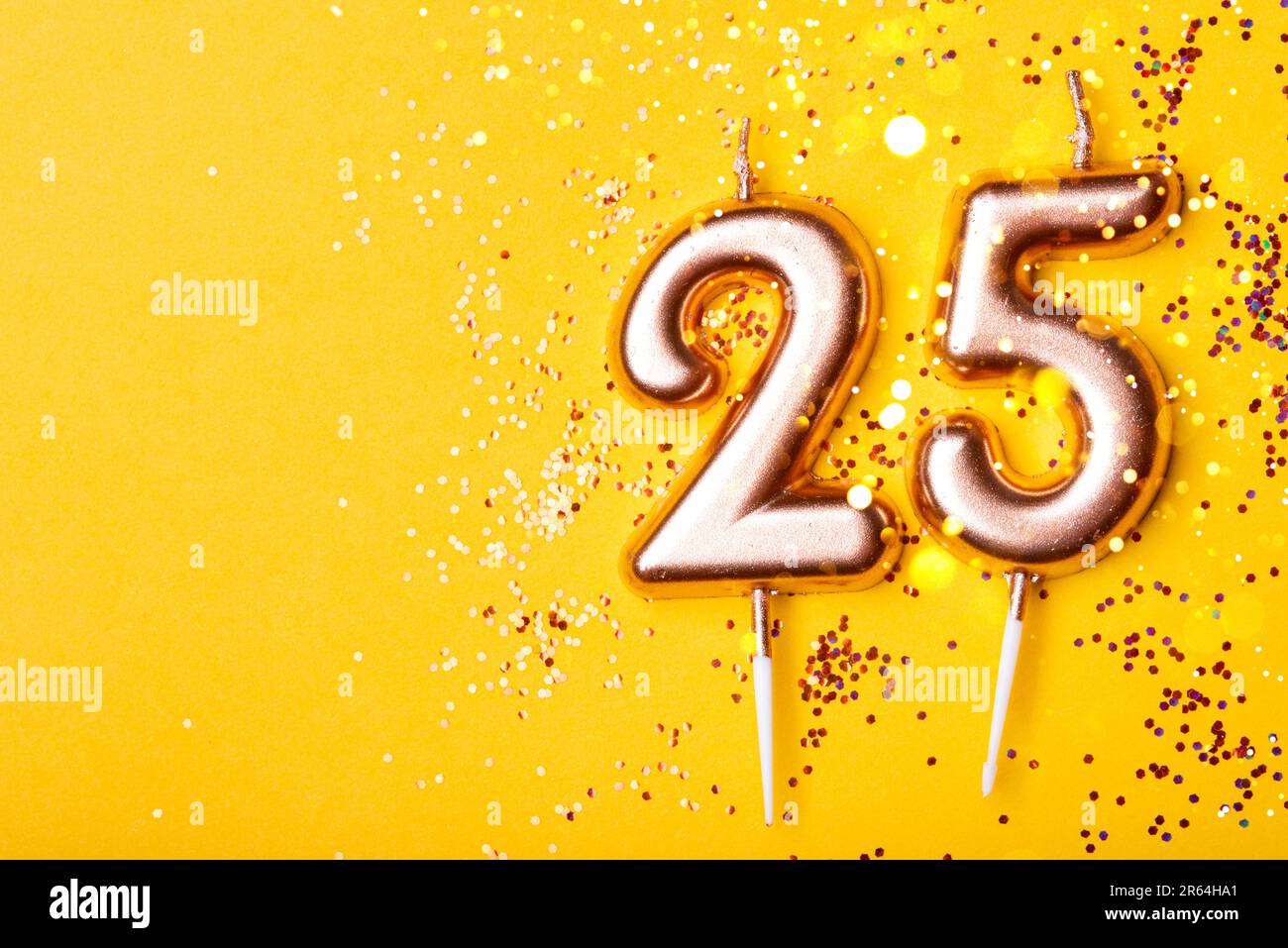 Gold candles in the form of number twenty five on yellow background ...