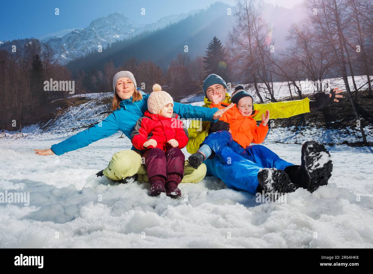 Family enjoys snowy alpine landscape, hugs and sits together Stock ...