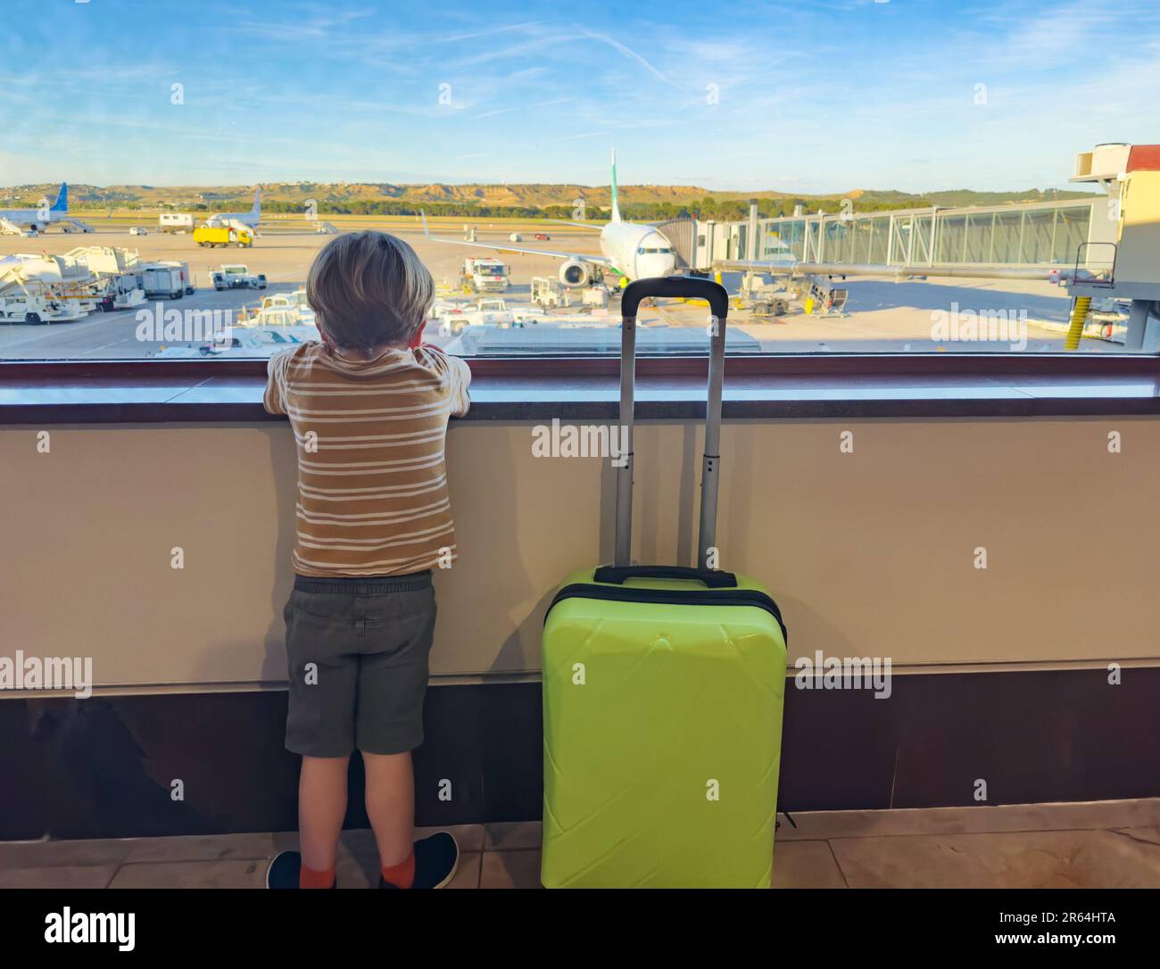 Small child stands on near gate at airport with a green suitcase Stock ...