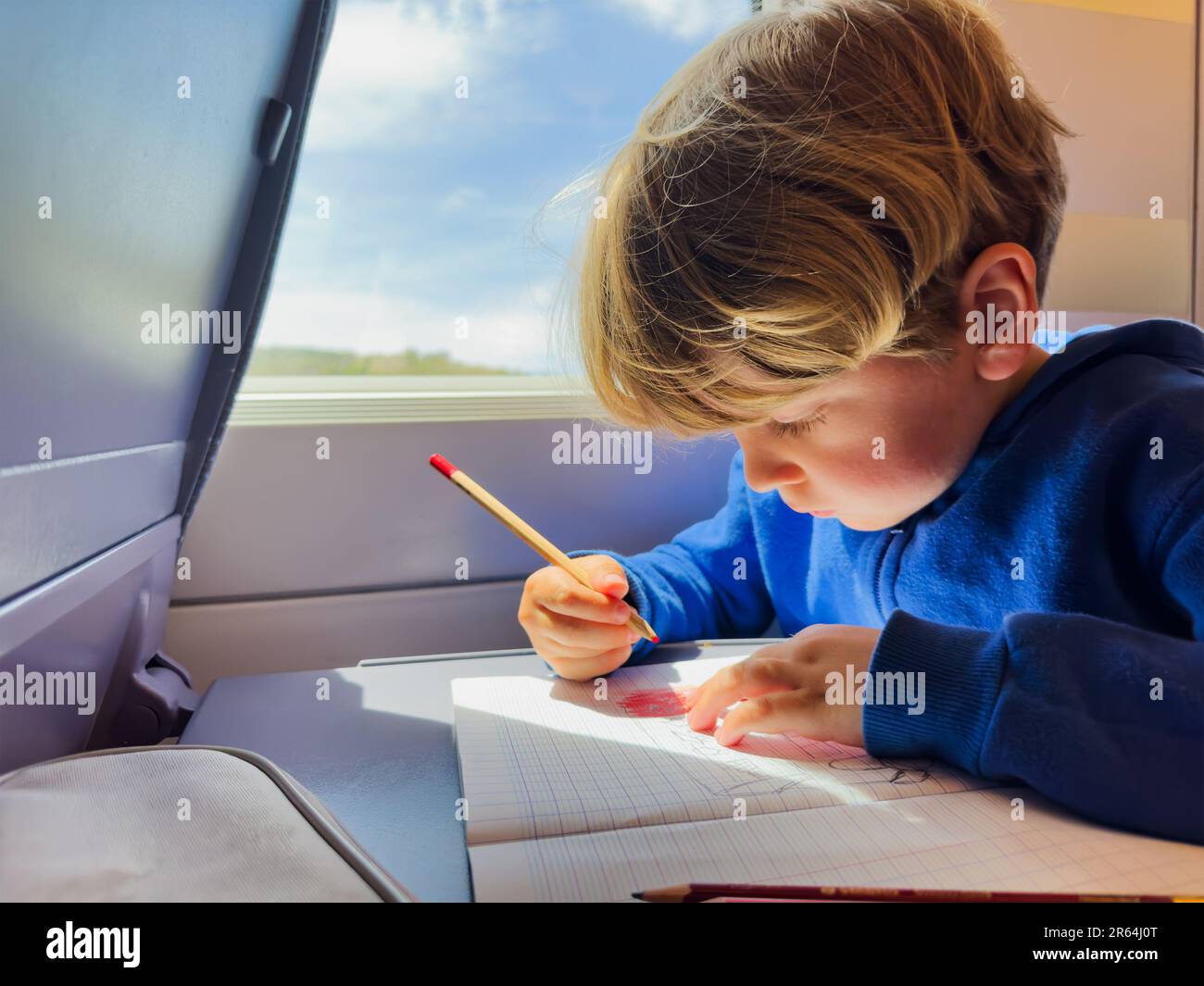 Cute boy on high-speed train writes in the notebook Stock Photo - Alamy