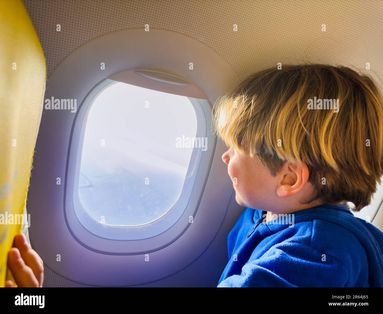 Handsome little boy sit and look at the window in plane Stock Photo - Alamy