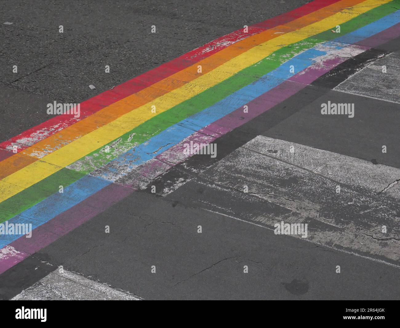 A vibrant rainbow mural is painted on the side of a street, adding a ...