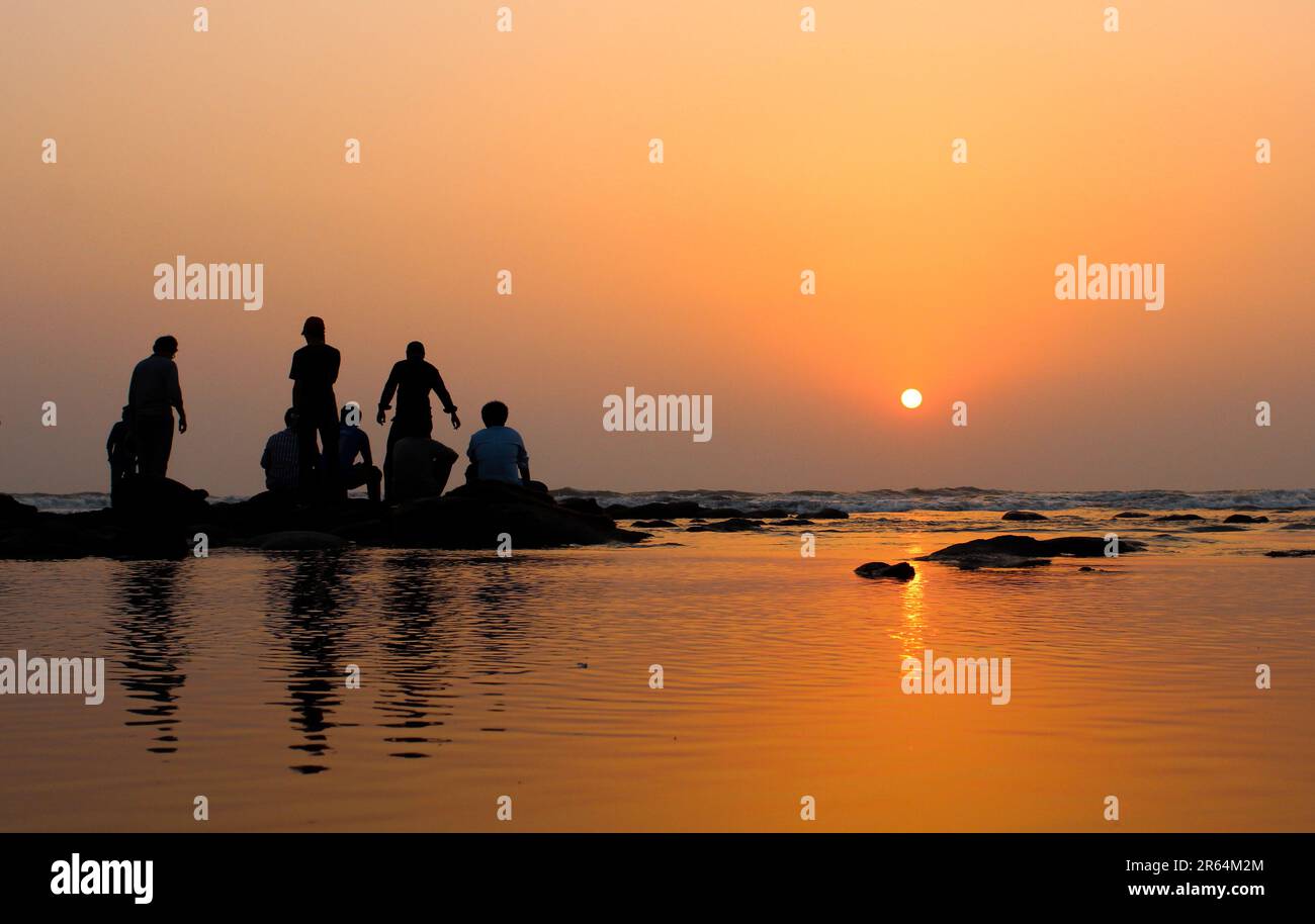 Friends chatting on a beach during sunset. Beautiful sun set with ...