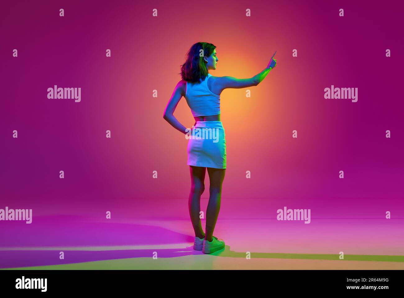 Portrait of a young girl standing and touching an imaginary screen over ...