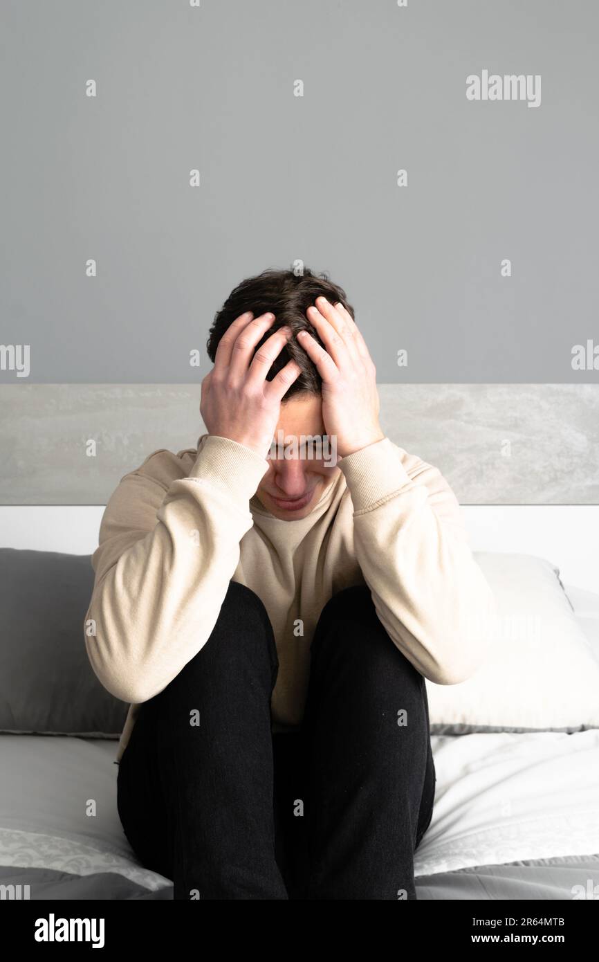 Sad young man laments sitting his bed Stock Photo - Alamy