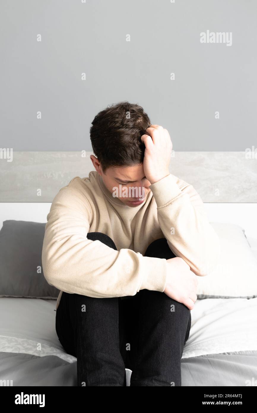 Sad young man laments sitting his bed Stock Photo - Alamy