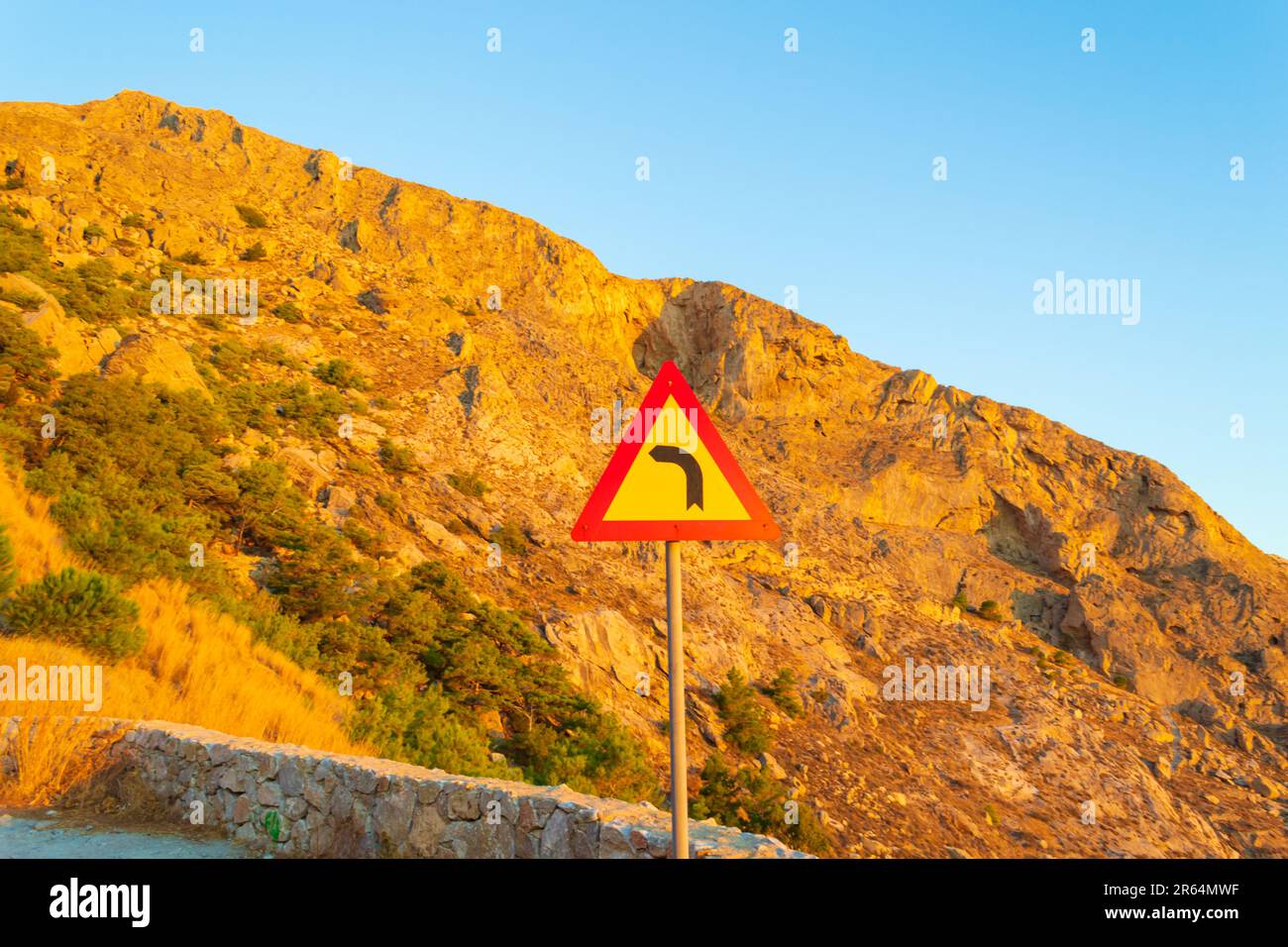 Road sign for left bend at Mesa Vouno coloured by the sunrise,It is a ...