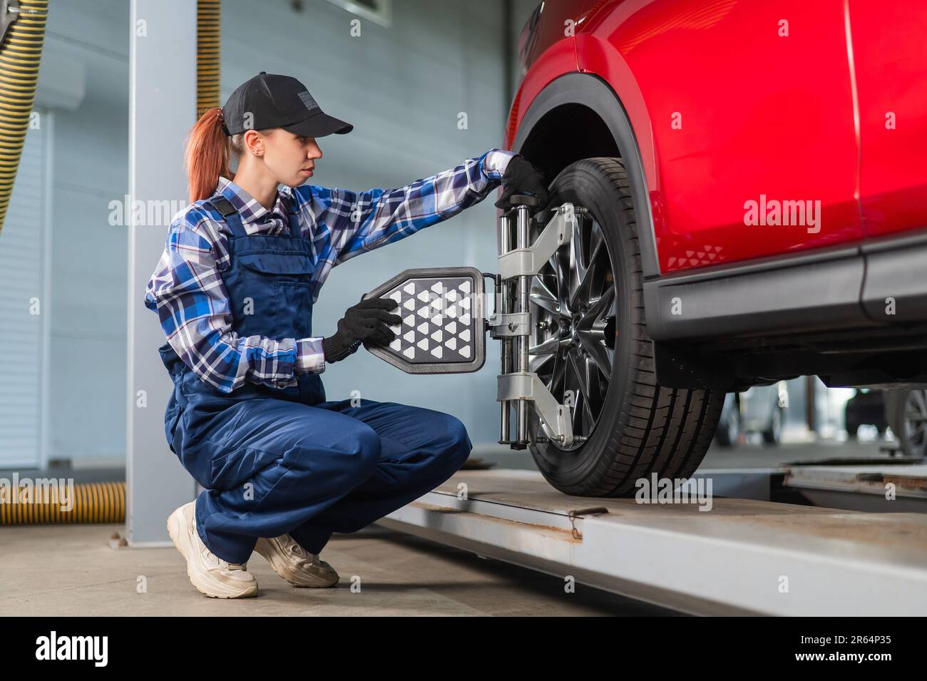 A female auto mechanic makes a camber. Woman working in a car service ...
