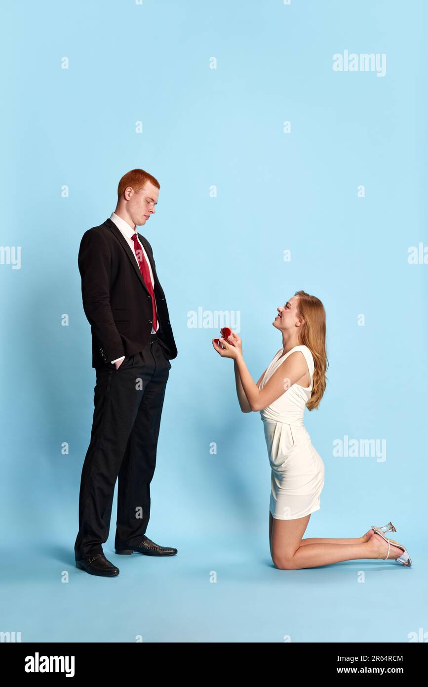 Young beautiful woman in white dress standing on knees, proposing to ...