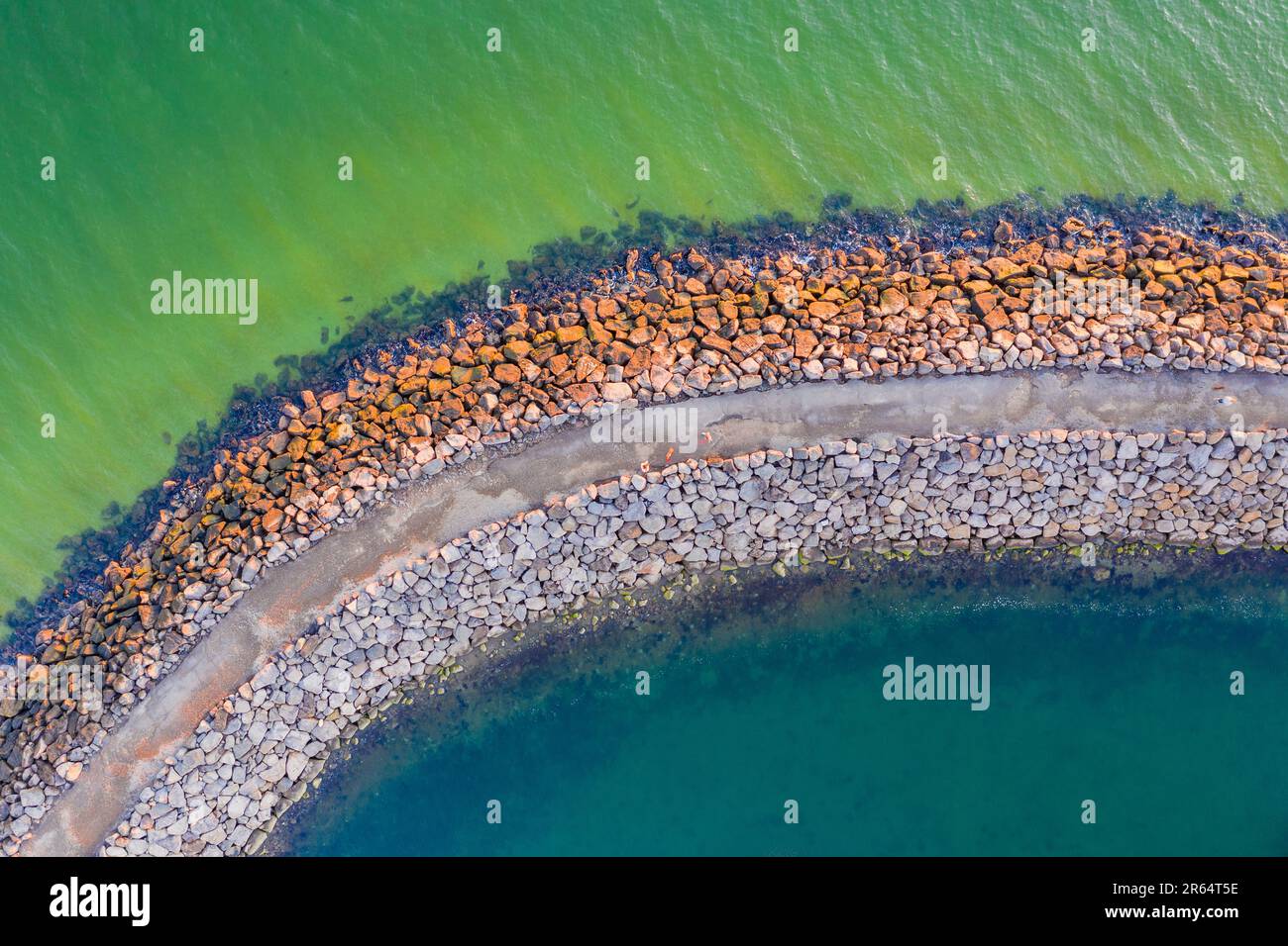 Aerial view of a rocky breakwater with different coloured water on each ...
