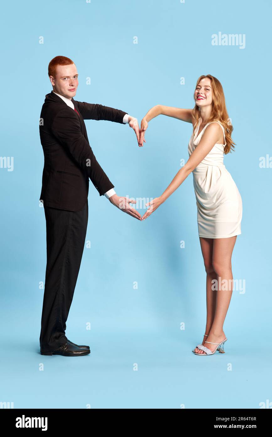Happy, delightful young couple, man and woman in suit and dress making ...
