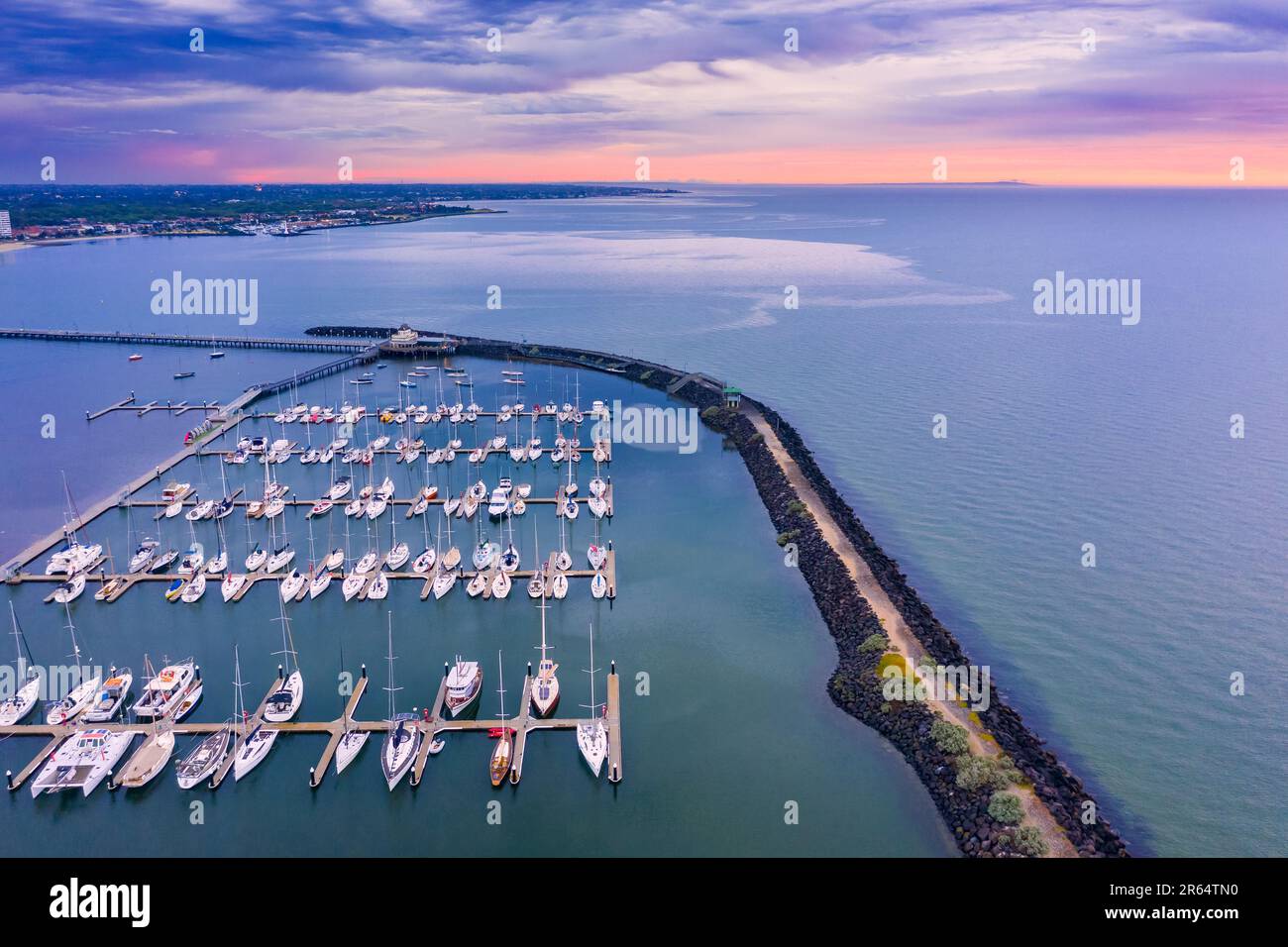 Aerial view of boats at a marina inside a breakwater with a coloured ...