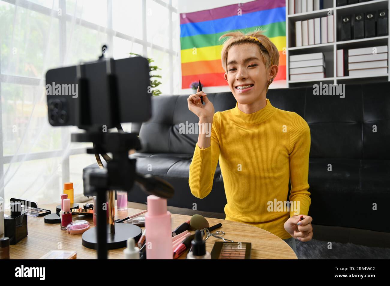 Cheerful male beauty blogger recording makeup tutorial in home studio ...