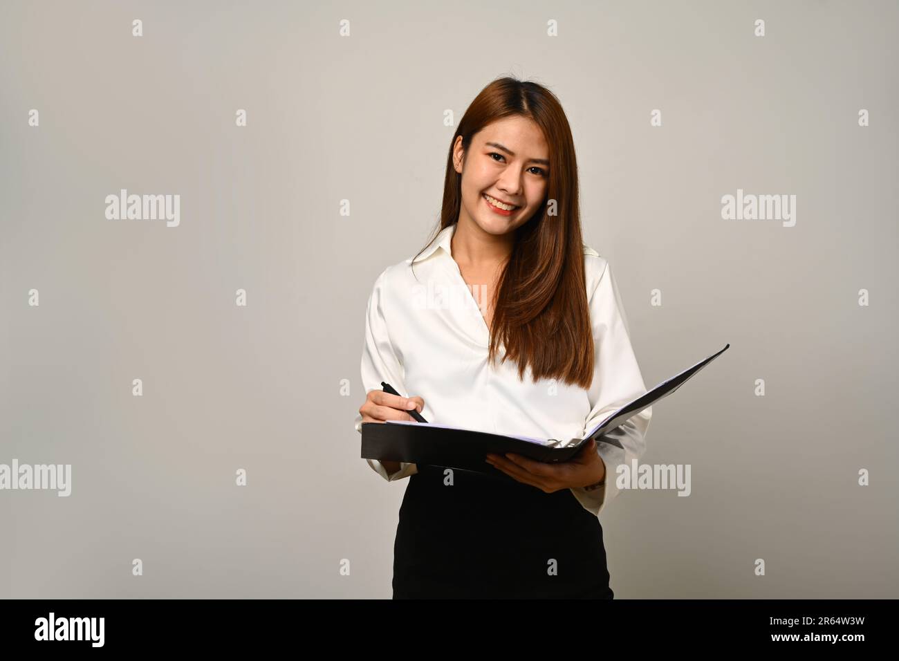 Gorgeous young business woman holding open binder and smiling to camera ...
