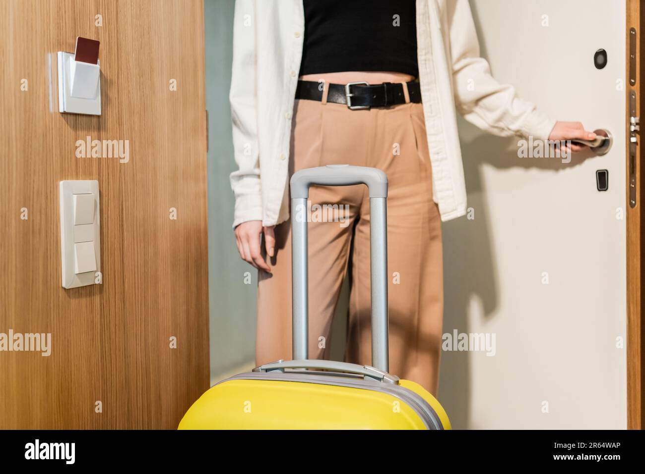 cropped view of young and stylish woman in white shirt and beige pants ...
