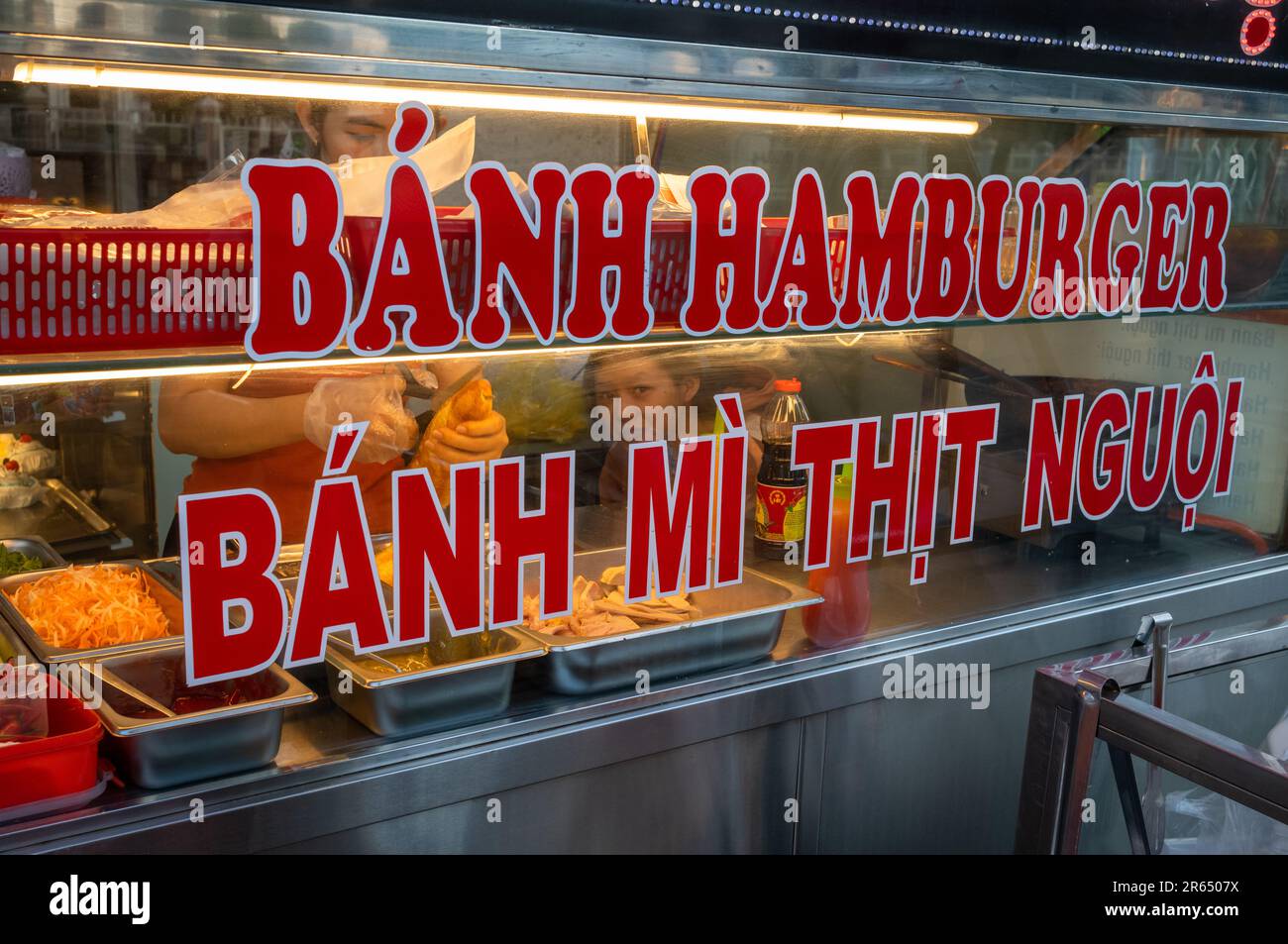 Two young women prepare traditional Vietnamese banh mi sandwiches in a ...