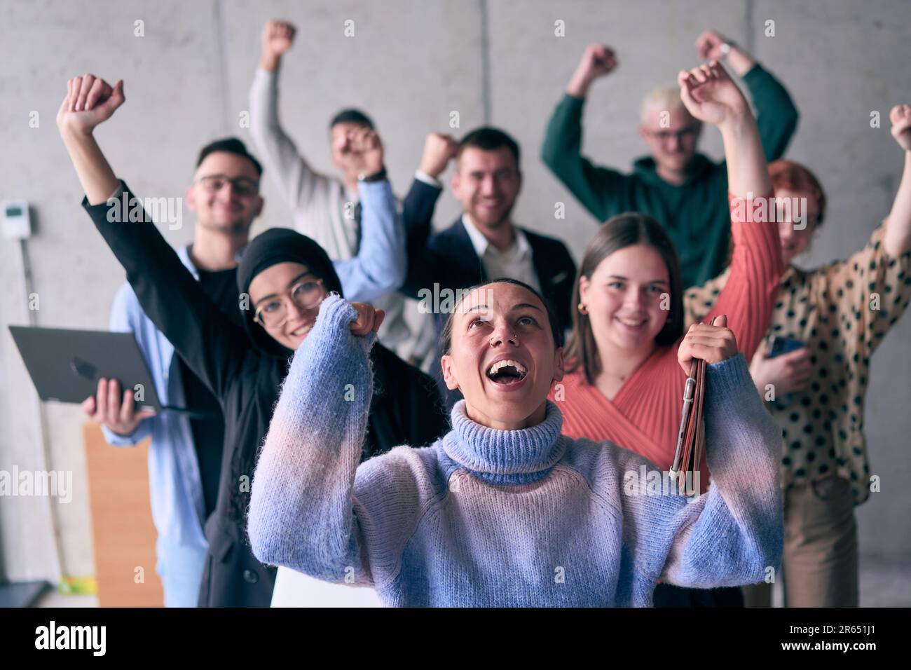 A diverse group of successful businessmen raises their hands in the air ...