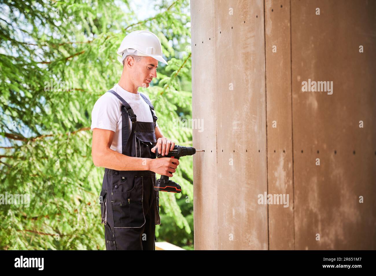 Carpenter constructing wooden framed house. Man worker cladding facade ...
