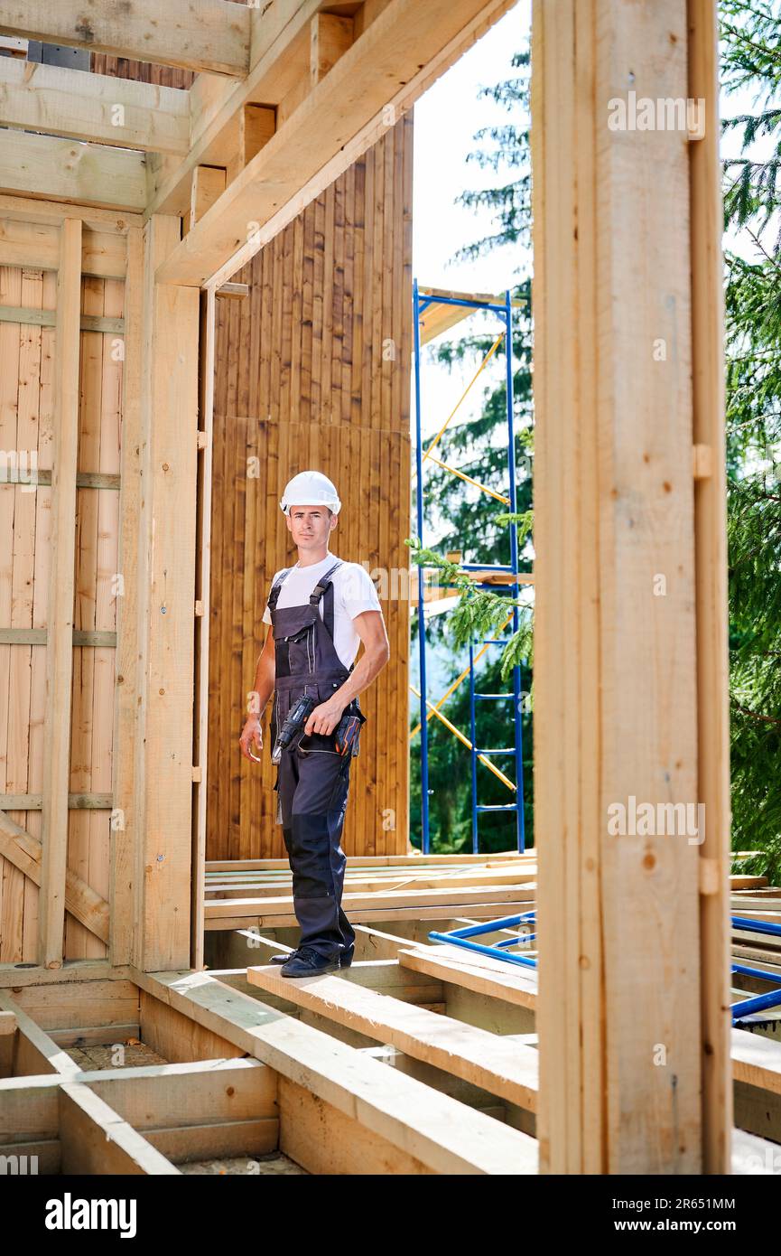 Portrait of carpenter constructing wooden framed house. Man worker ...