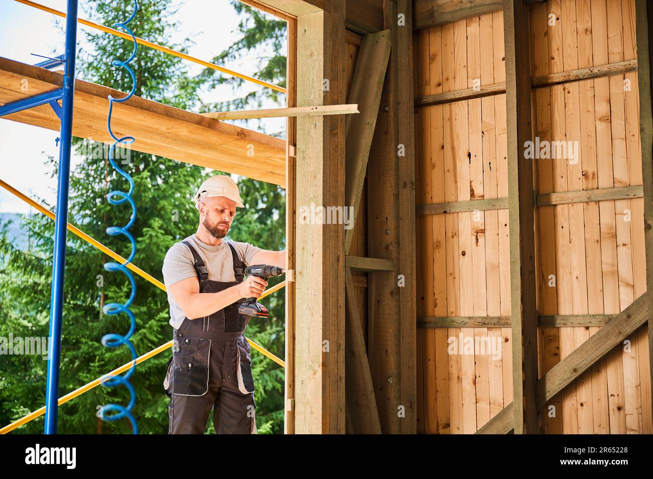 Carpenter constructing wooden framed house. Bearded man worker cladding ...