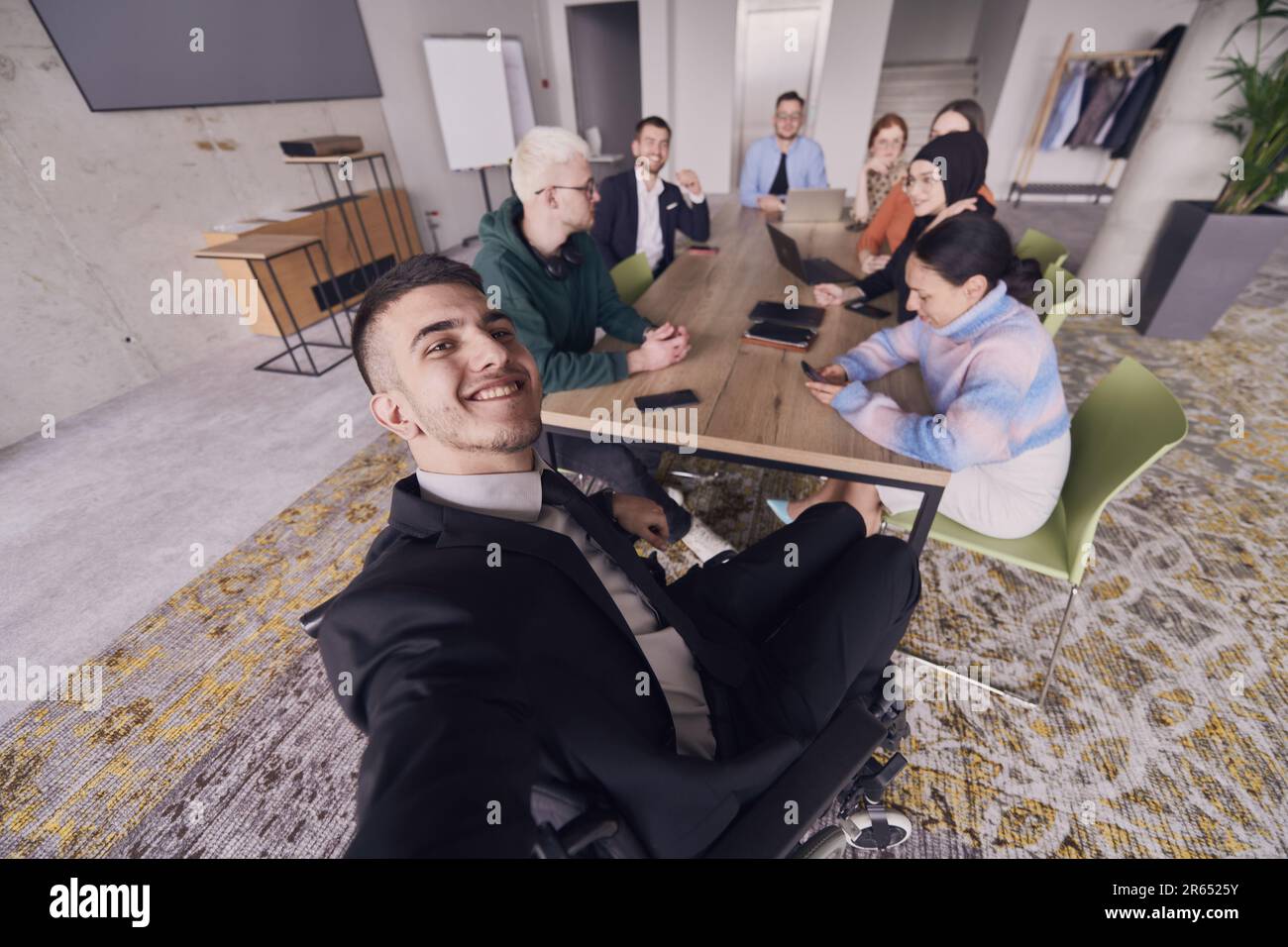 In a modern office, a group of businessmen gathers around a table ...
