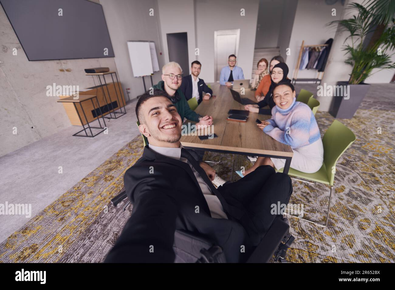 In a modern office, a group of businessmen gathers around a table ...