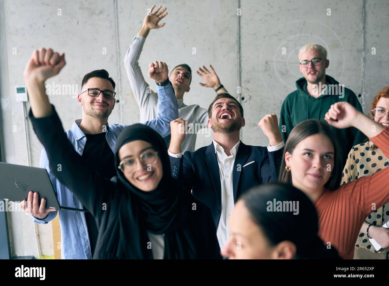 A diverse group of successful businessmen raises their hands in the air ...