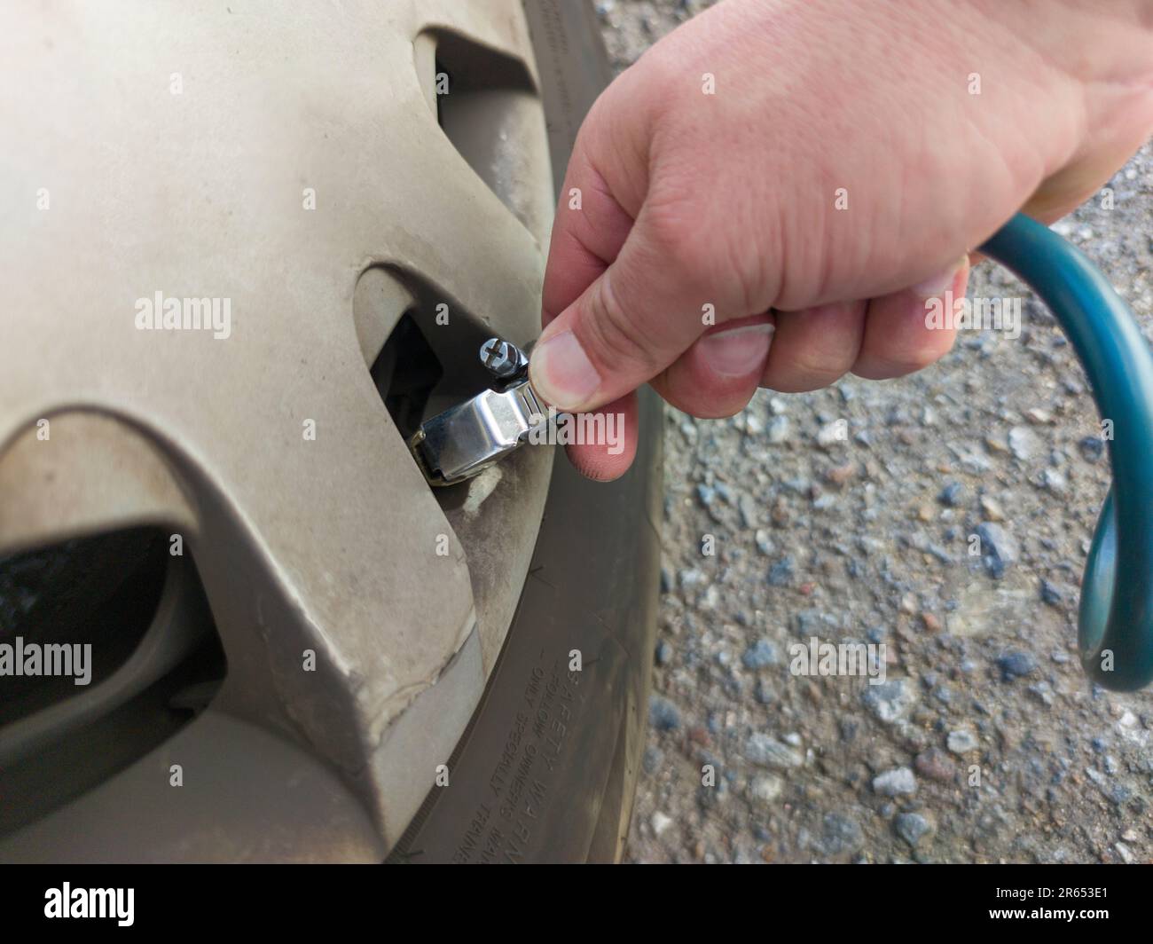 Road user Inflating the tyre at petrol station. Hand holding the valve ...