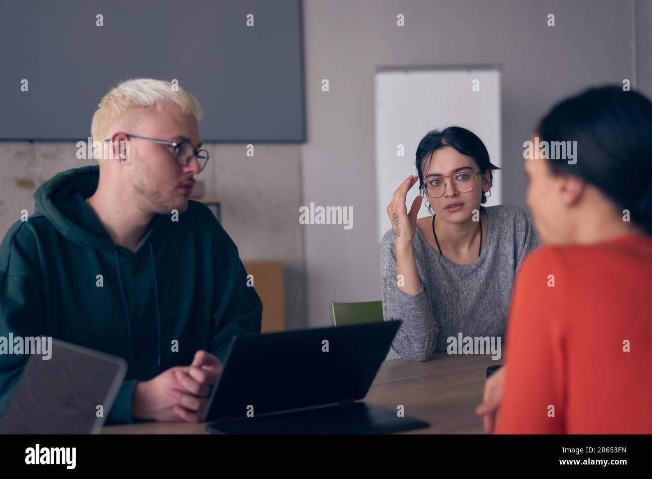 A diverse group of business professionals gathered at a modern office ...