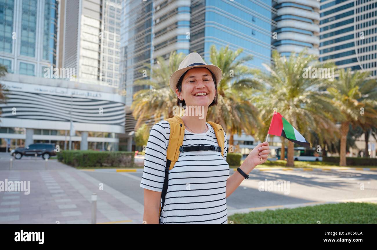 Happy young asian female traveler with backpack and hat with UAE flag ...