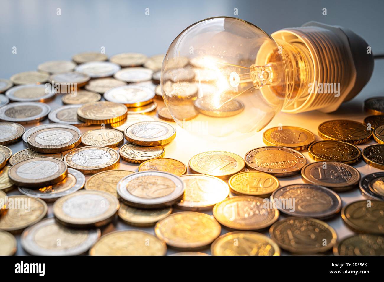 Light bulb turned on, with coins around. Increase in electricity ...