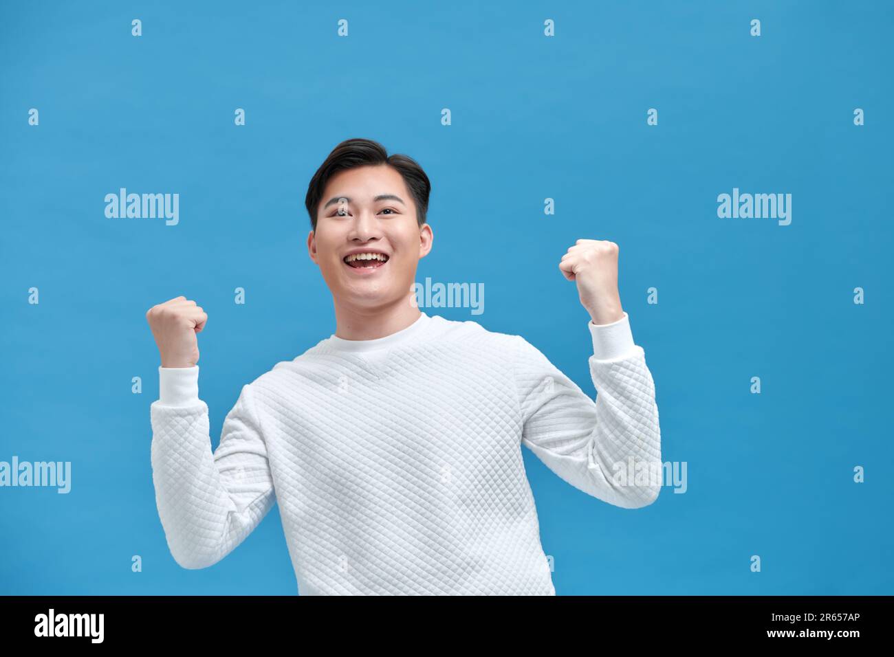Cheerful excited man standing isolated over blue background ...