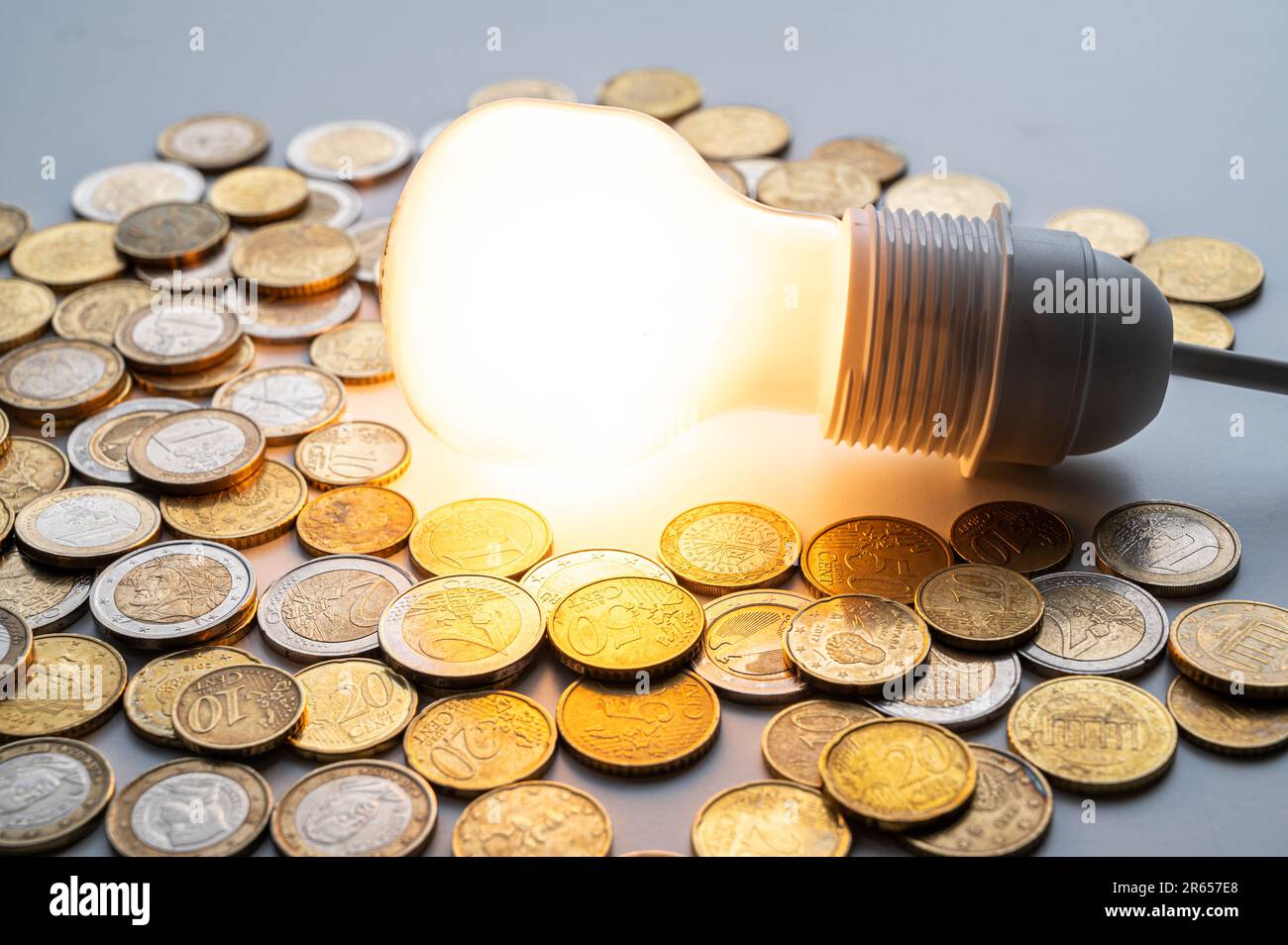 Light bulb turned on, with coins around. Increase in electricity ...