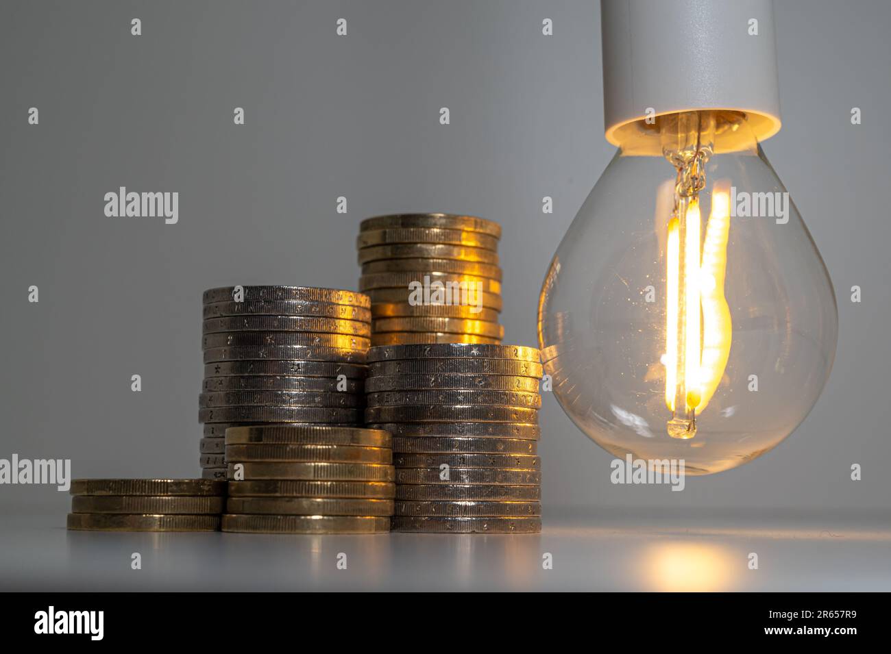 Light bulb turned on, with stacks of coins next to it. Rising ...