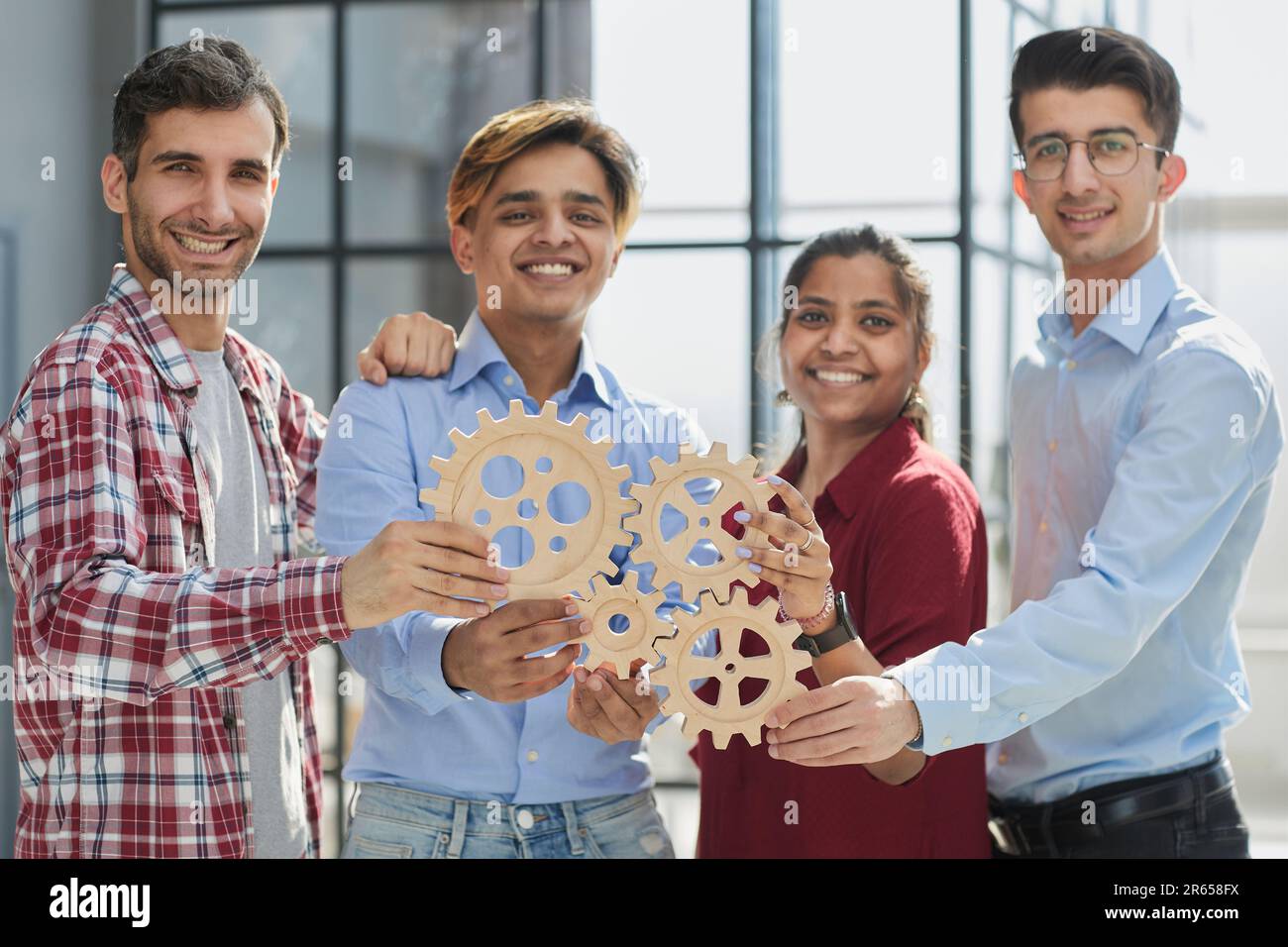 Business people or office workers hold wooden gears that symbolize well ...