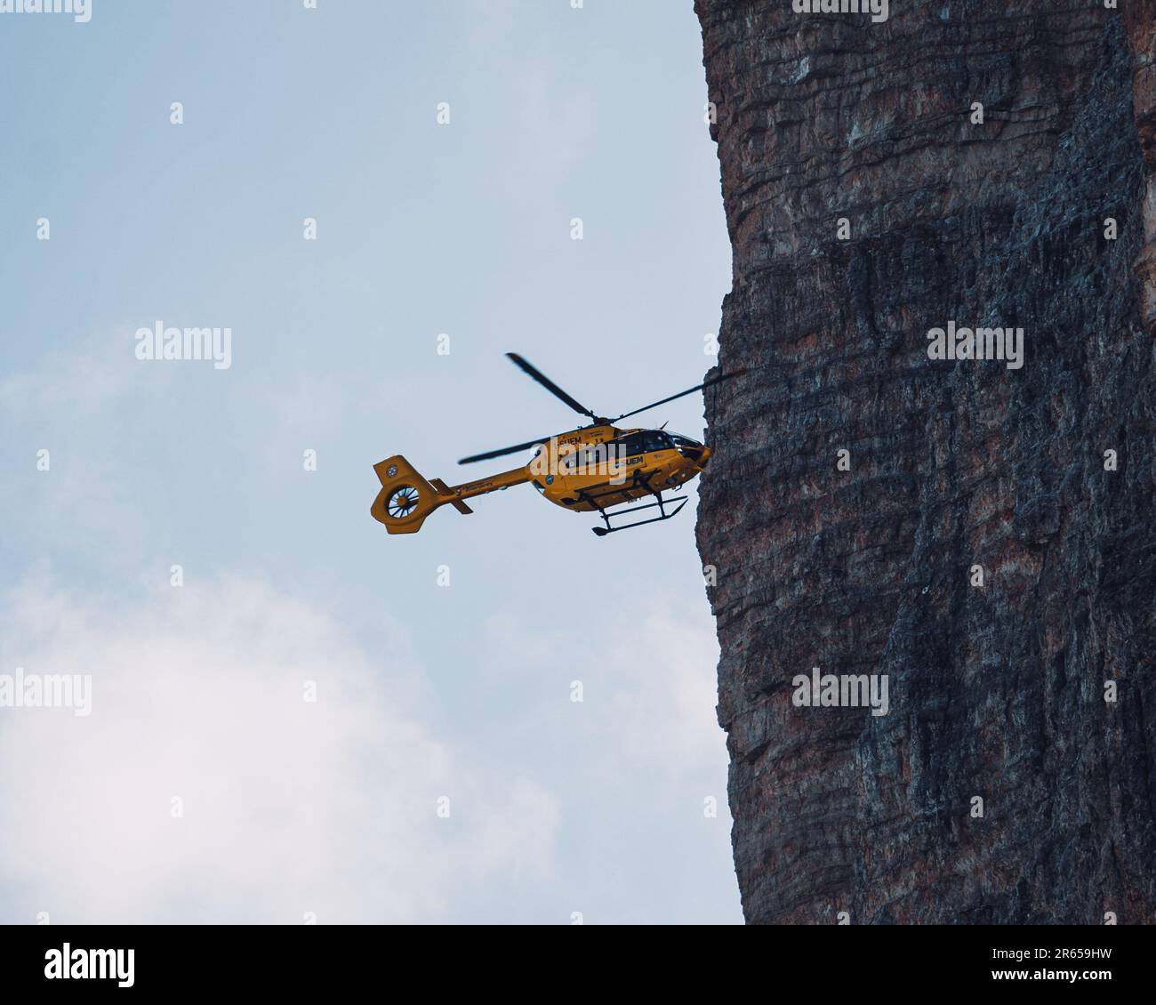 An aerial view of a helicopter flying above a rocky cliff, providing an ...