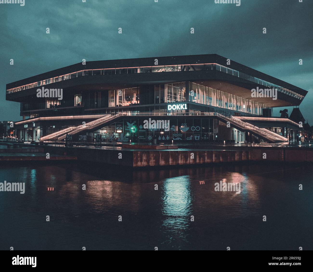 This image is a nighttime shot of a building with its lights glowing ...