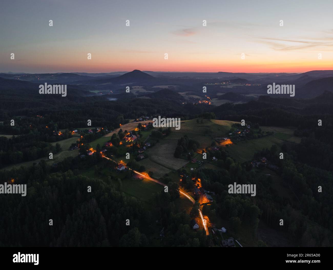An aerial long exposure of a car driving on a road in an idyllic rural ...