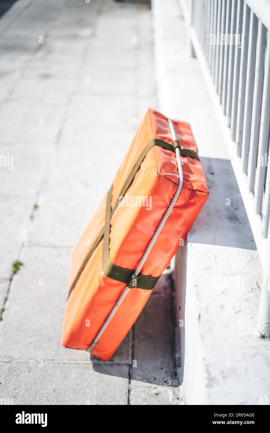 A bright orange pool float against a textured concrete wall beside a ...