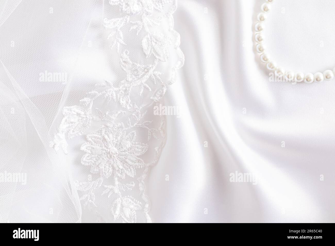 White lace bridal veil on a satin background with soft waves, pearl ...