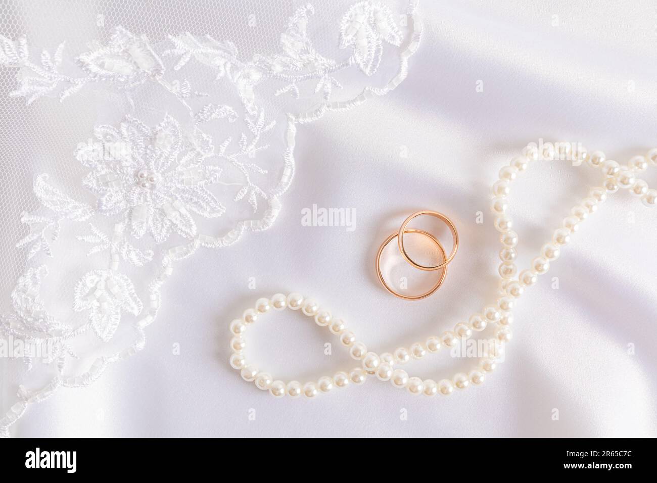 Beautiful wedding background. Two gold wedding rings on white satin ...