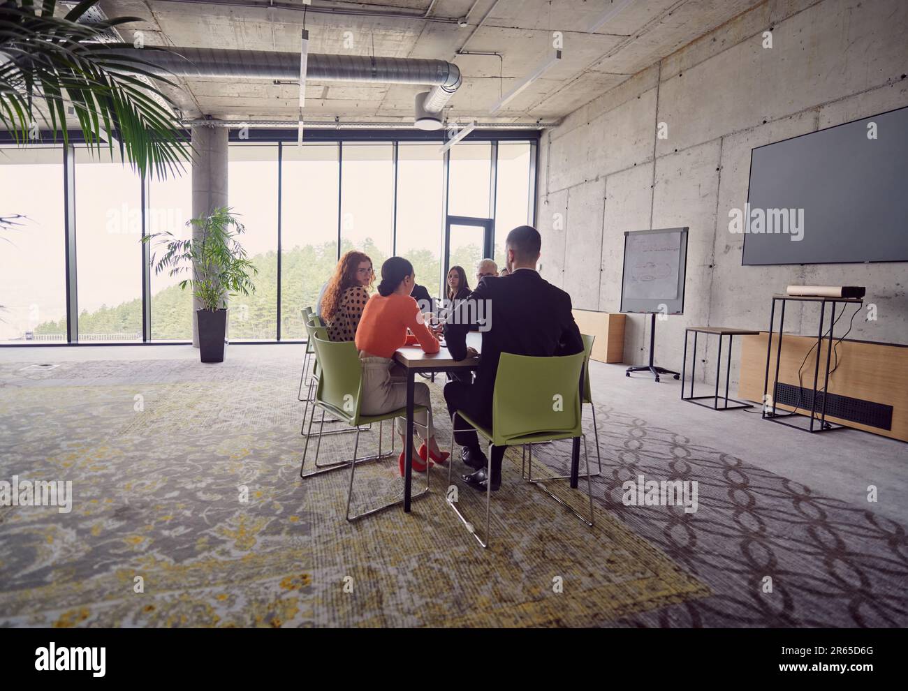 A diverse group of business professionals gathered at a modern office ...