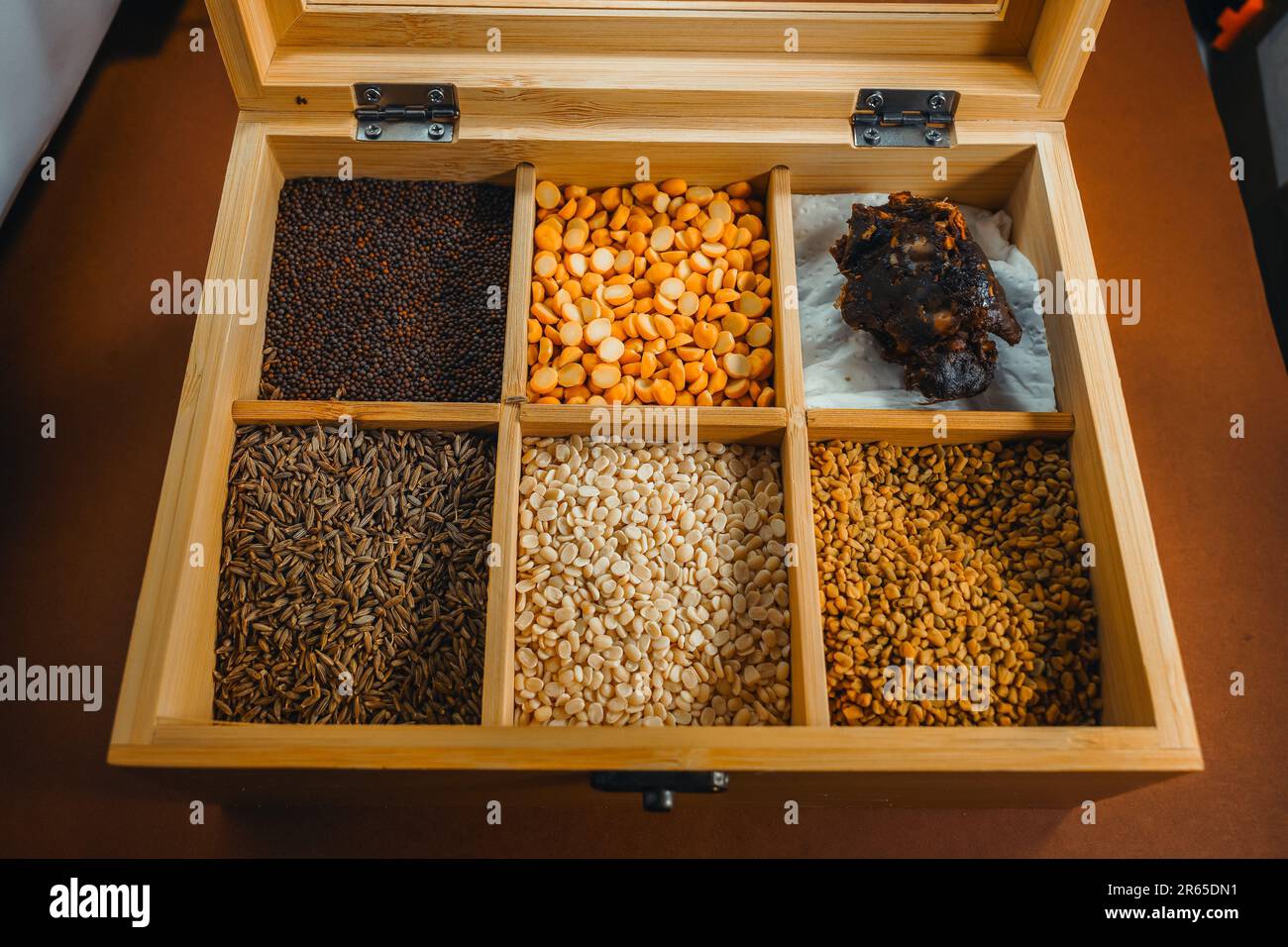 A brown wooden box with multiple sections containing a variety of ...