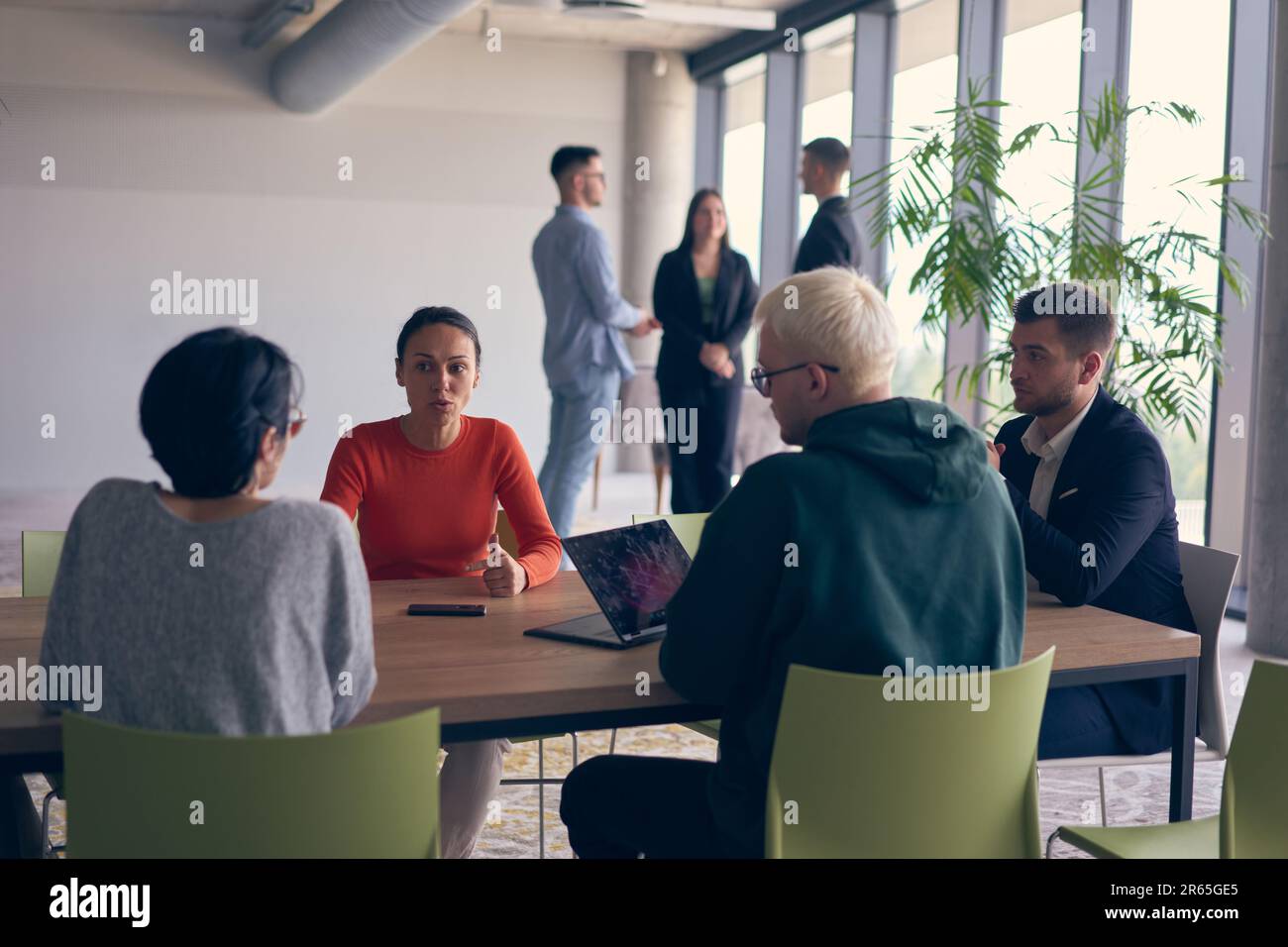 A diverse group of business professionals gathered at a modern office ...